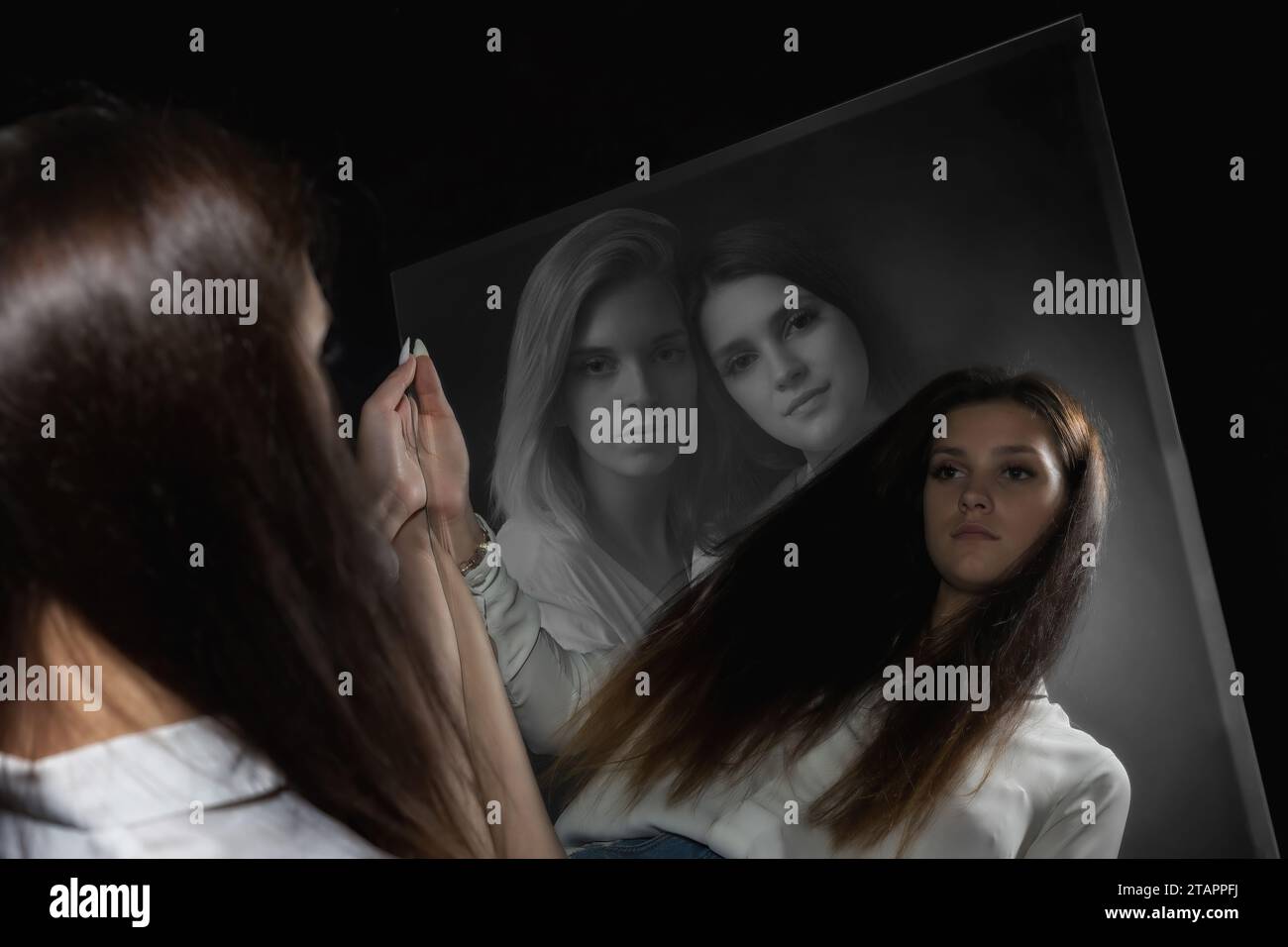 Young brunette girl is looking at her reflection in the mirror with ...