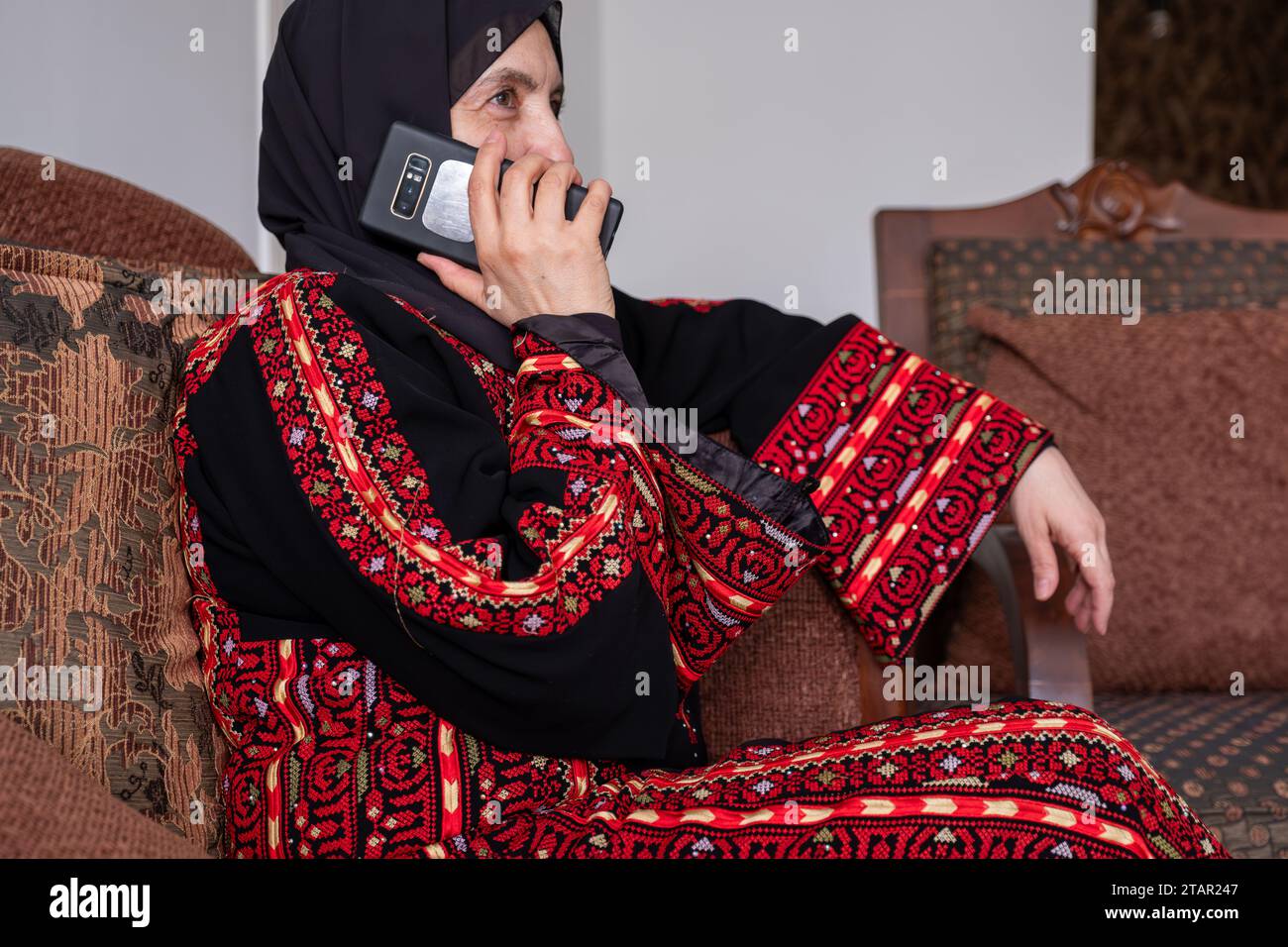 Female wearing palestinian traditional clothes indoor making phone call ...
