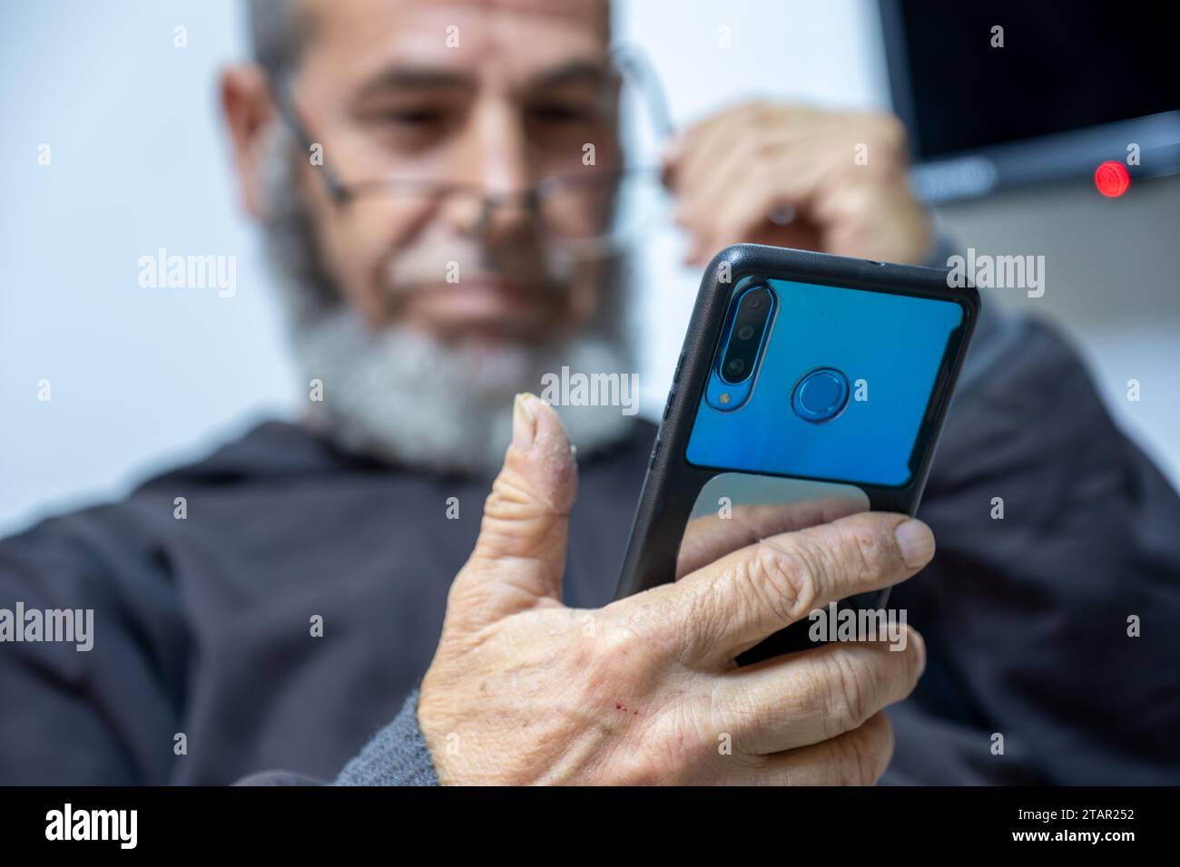 old man holding phone while focusing due to poor eye vision Stock Photo ...