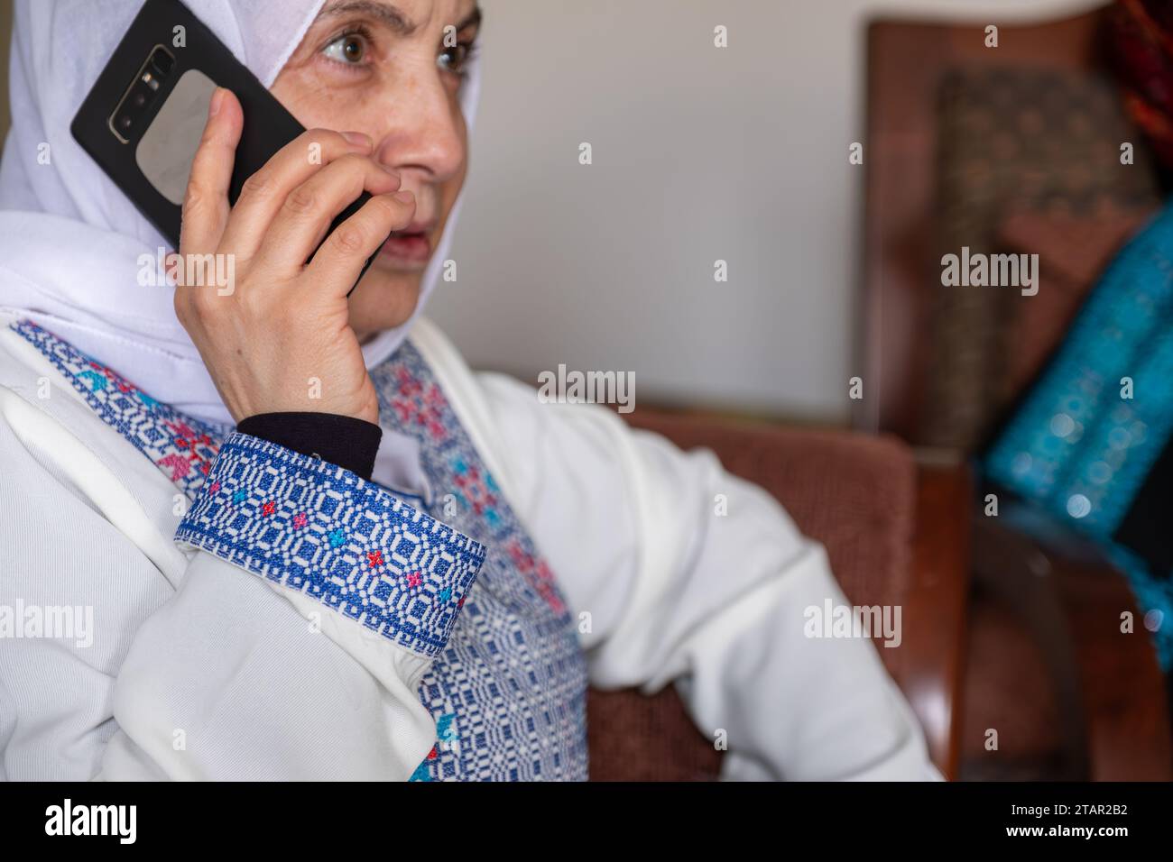Female wearing palestinian traditional clothes indoor making phone call ...