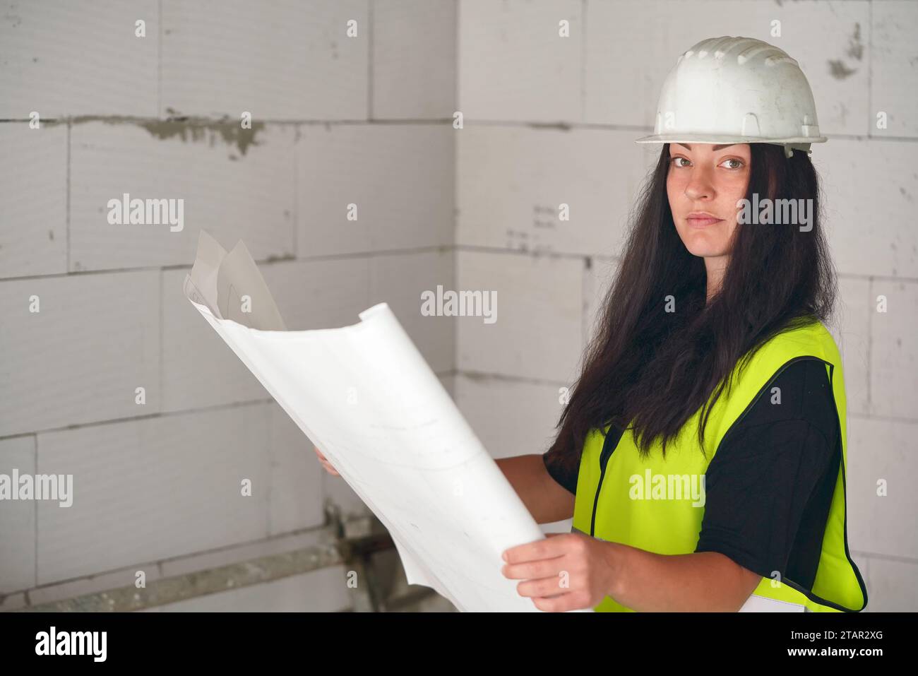 Young female construction worker in green high visibility vest and ...