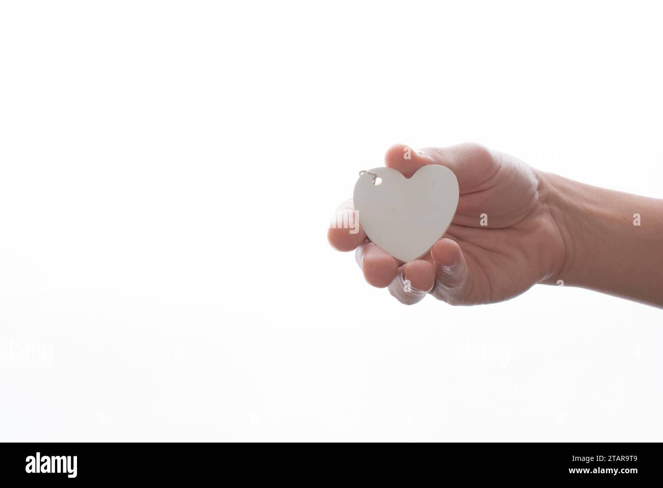 Heart shaped white object in hand on white background Stock Photo - Alamy