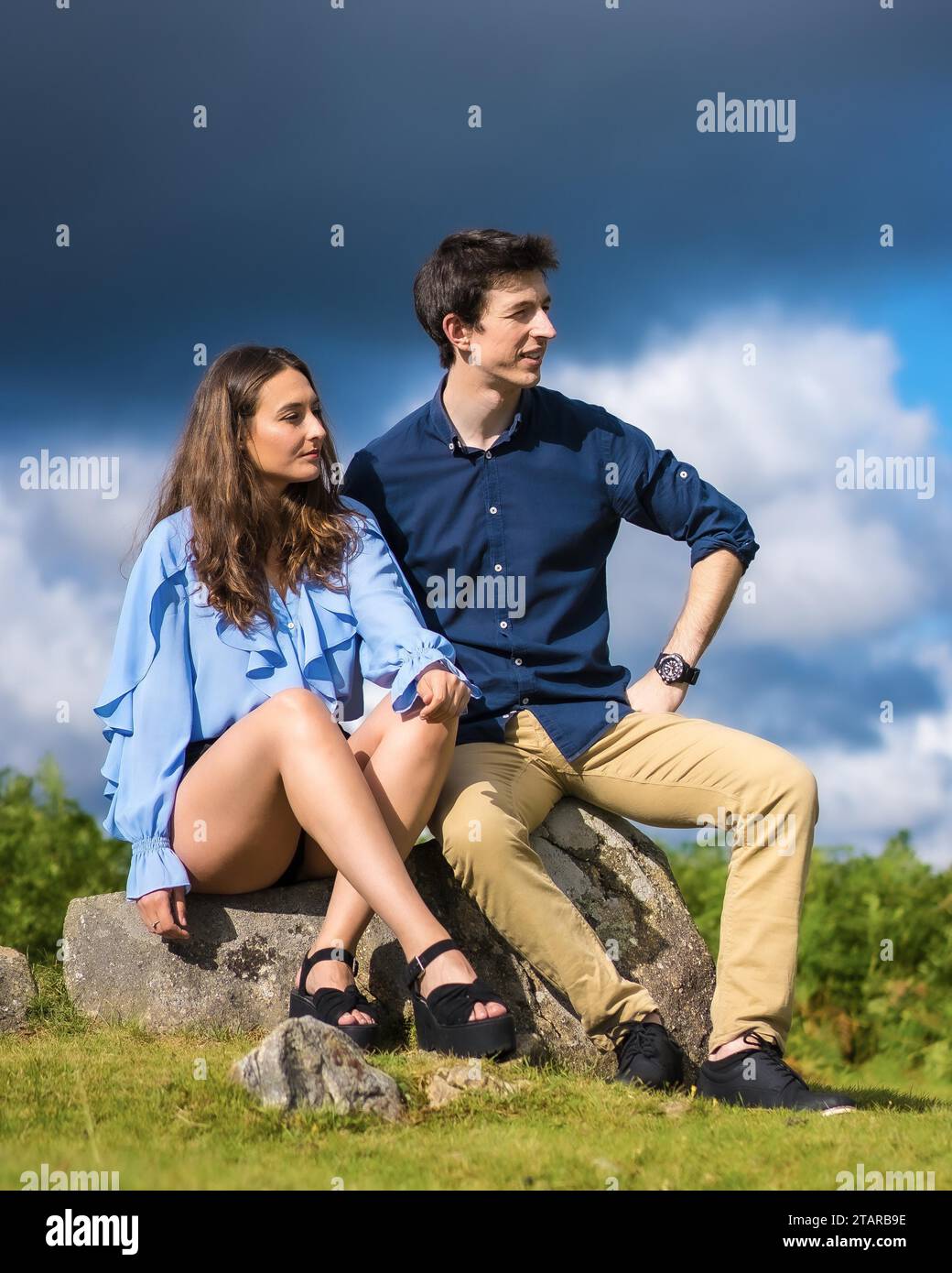 Vertical photo of young elegant couple gazing the horizon sitting on a ...