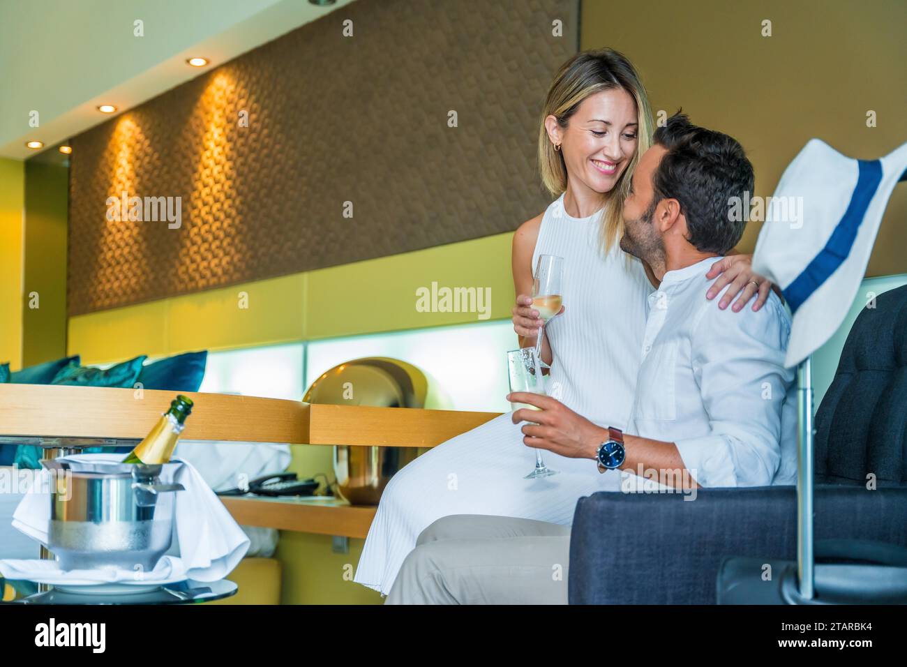 Couple drinking champagne in a luxury hotel room sitting on sofa next ...