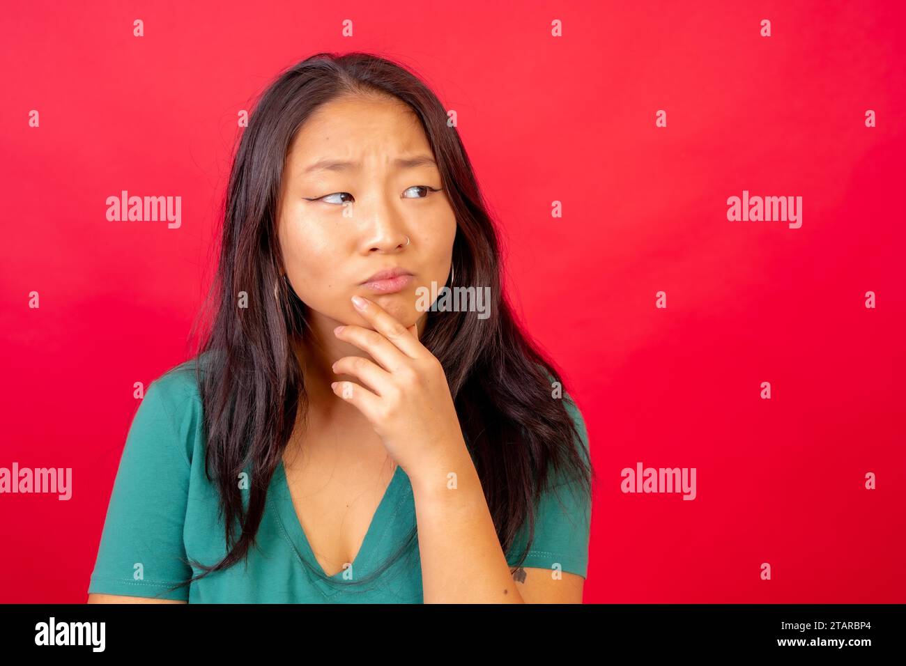 Studio photo with red background of a curious and doubtful chinese ...