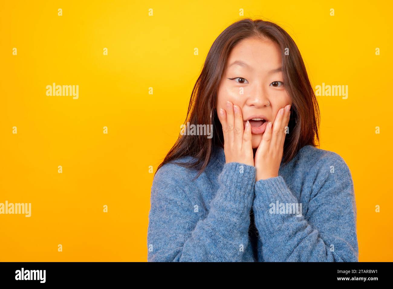 Studio photo with yellow background of a surprised chinese woman with ...