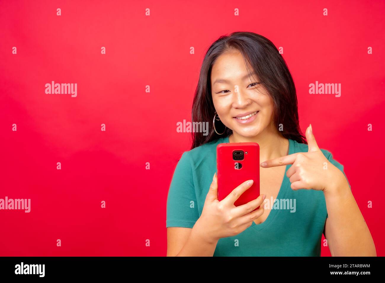 Studio photo with red background of a chinese woman pointing to a ...