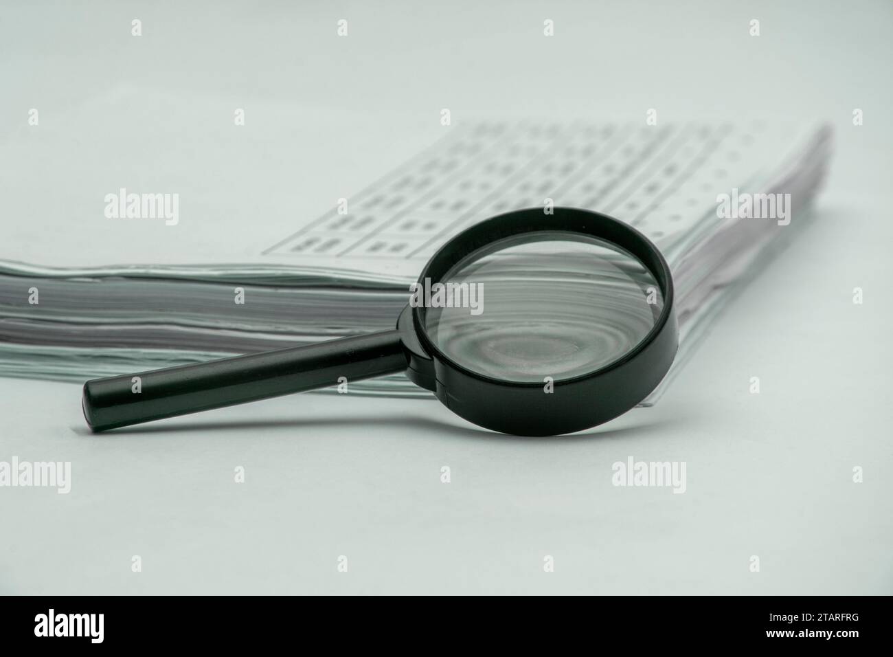 Background view of stacks of papers and magnifying glass on white ...
