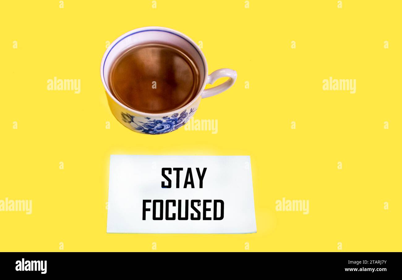 STAY FOCUS phrase on notepad and yellow background with cup of tea ...