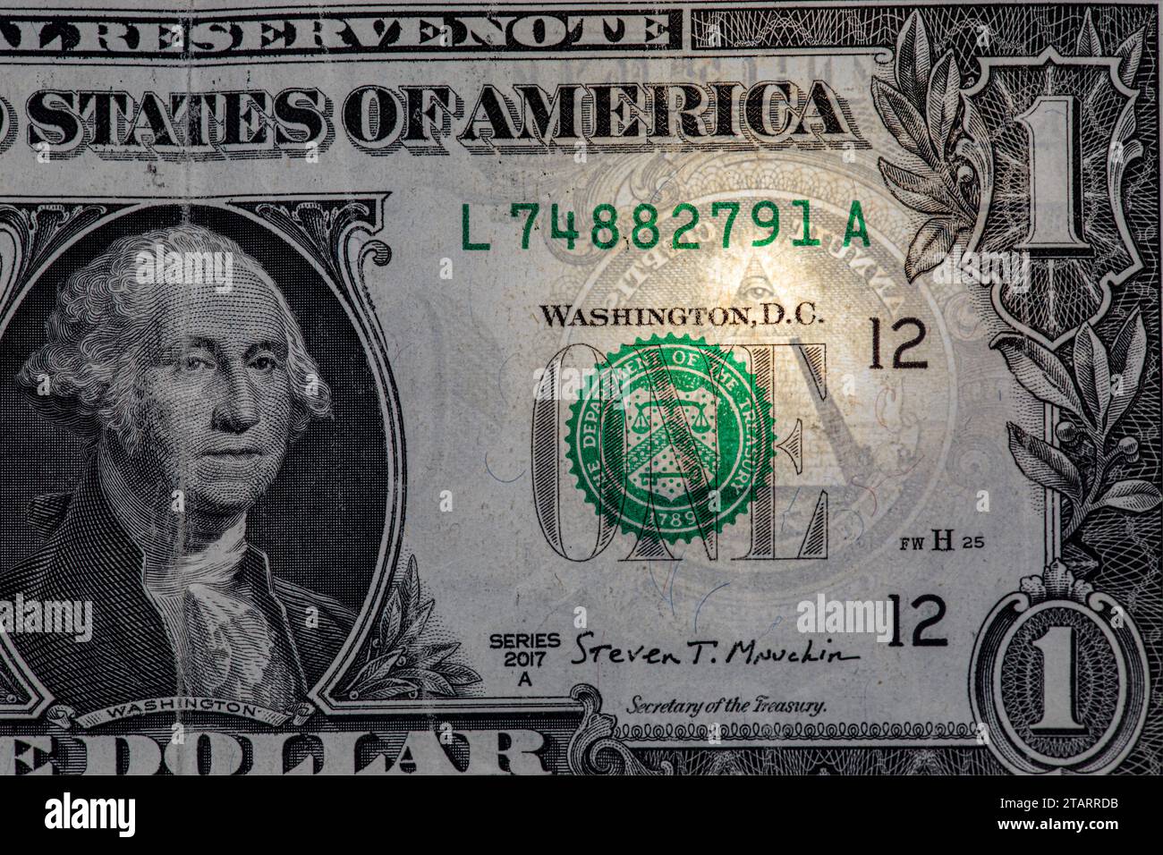 Close up of a one dollar bill with a small section of it backlit ...