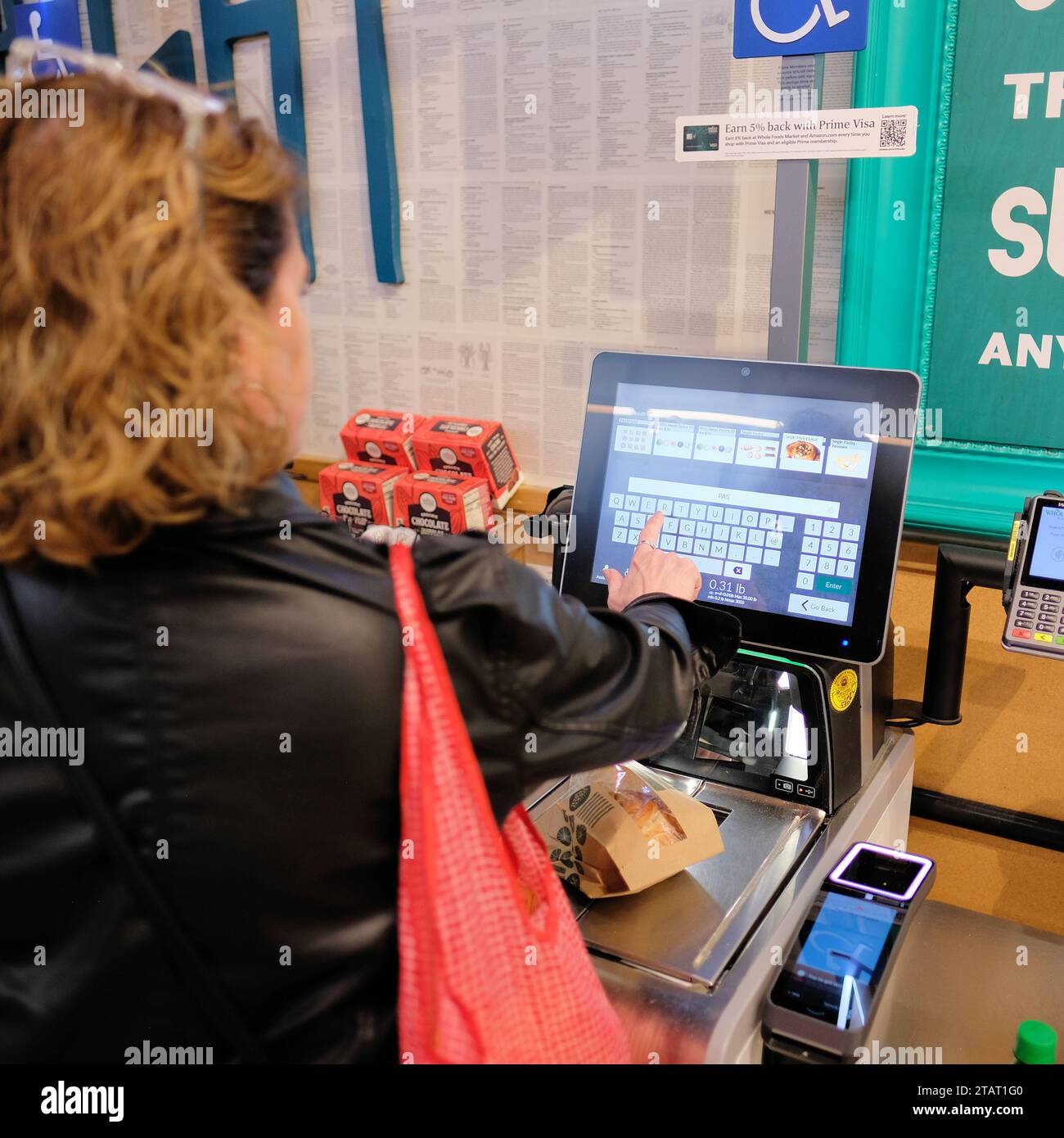 Woman customer checking out at an automated self-checkout register at a ...