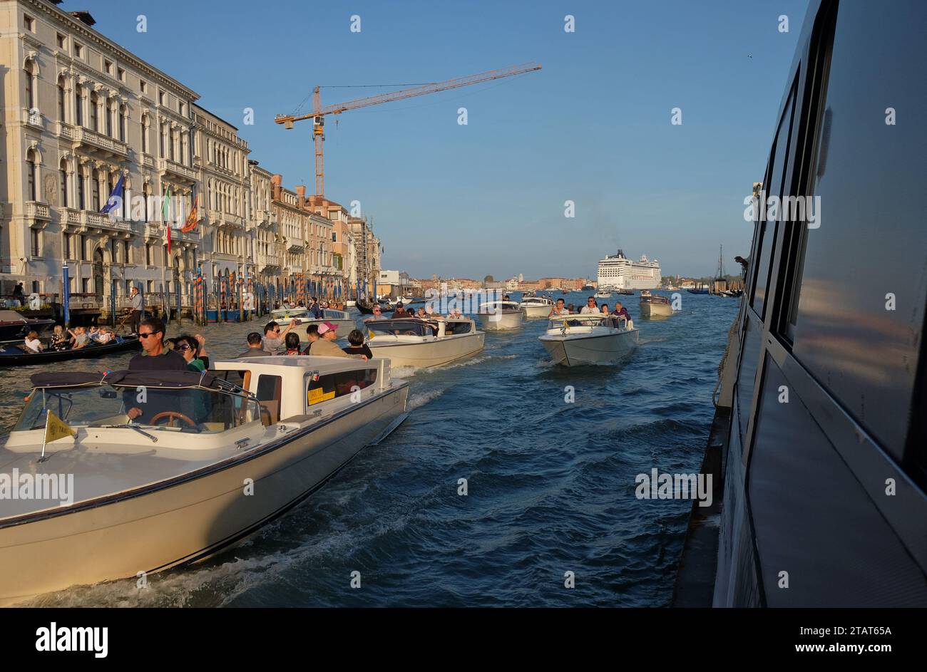Tourists in a convoy of water taxis pass gondolas and grand palazzo on ...