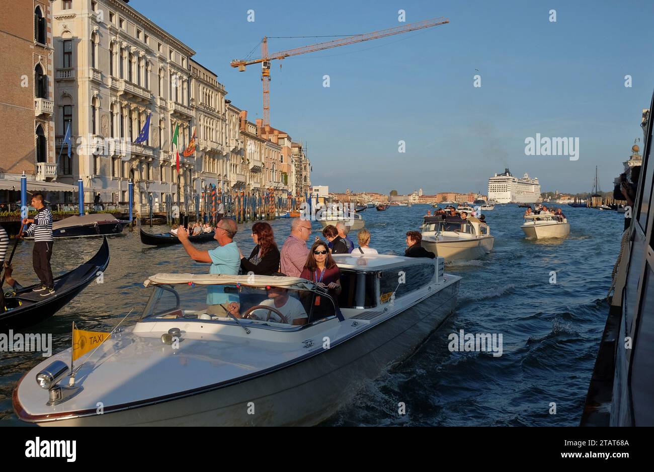 A convoy of water taxis ferry picture snapping tourists past gondolas ...