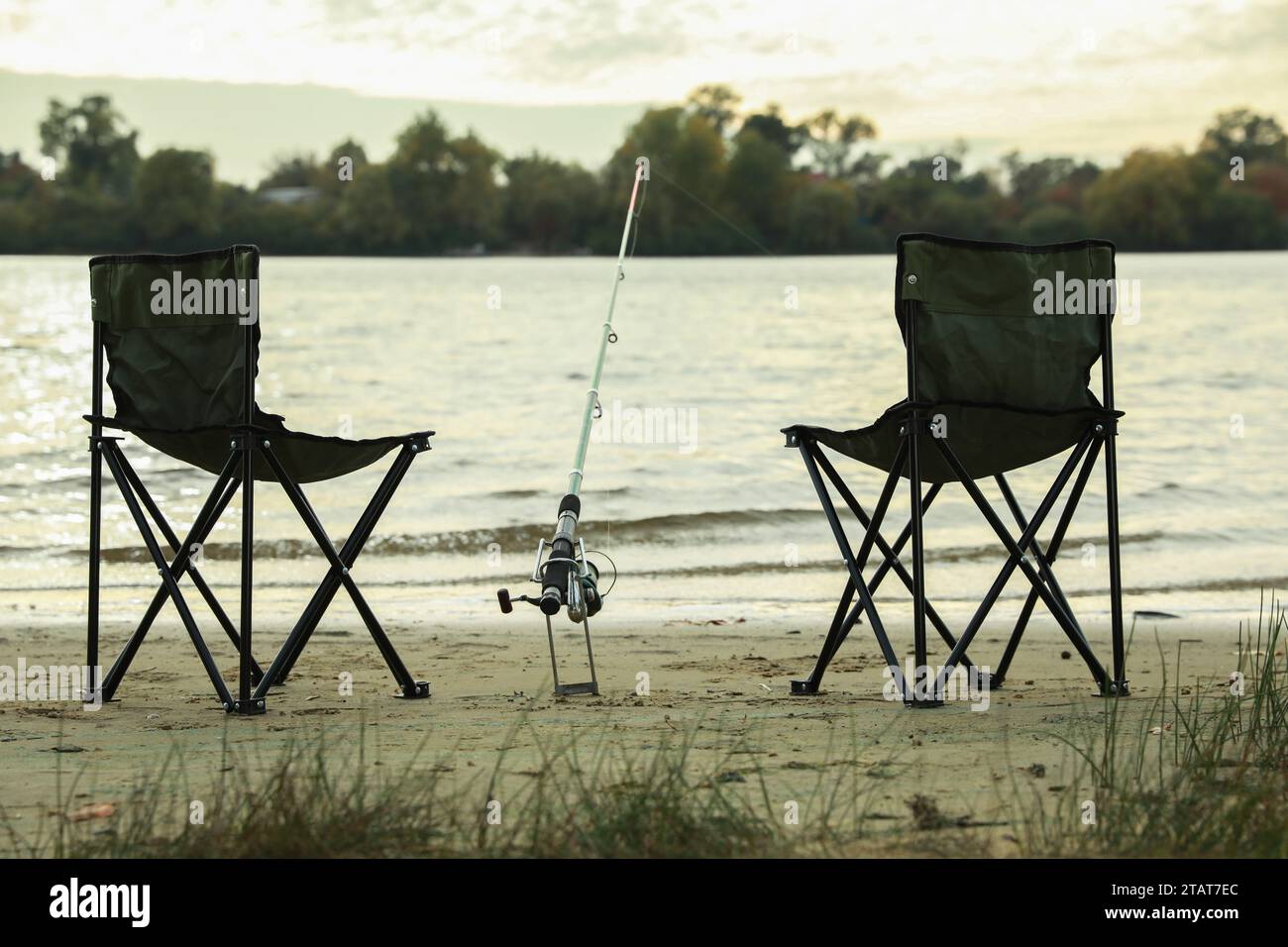 Folding chairs and fishing rod at riverside Stock Photo - Alamy