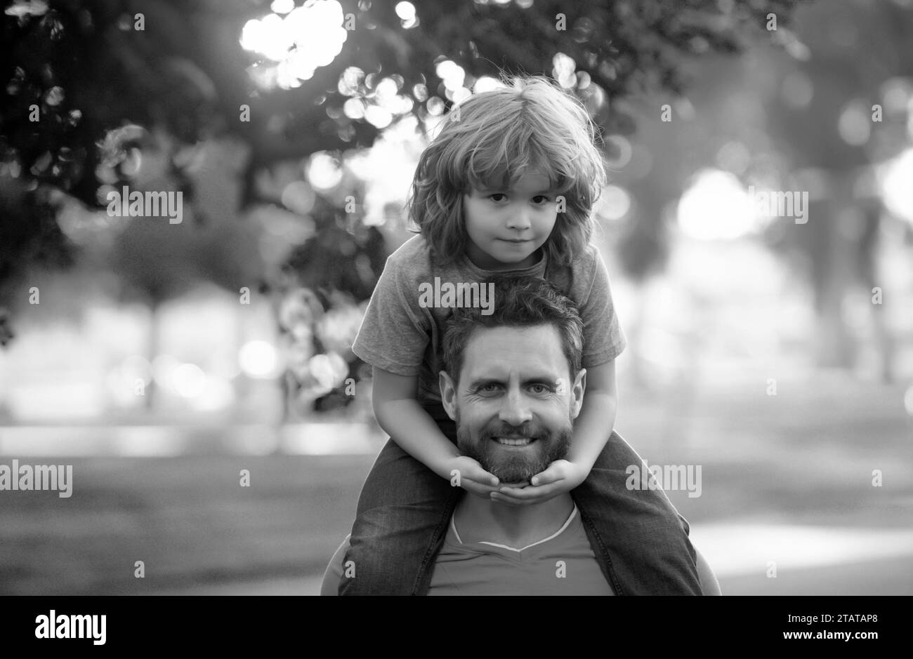 Father giving son ride on back in park. Portrait of happy father giving ...