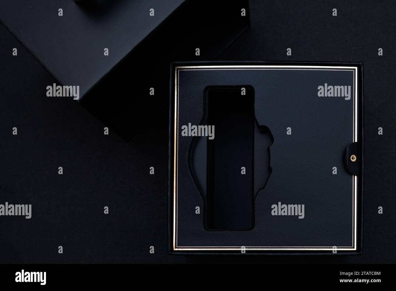 Empty elegant black smartwatch box with gold strip on black background ...