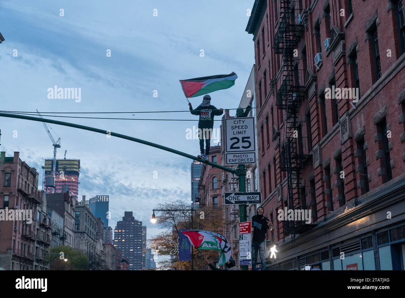 A man waving Palestinian flag while standing on top of ttraffic light ...