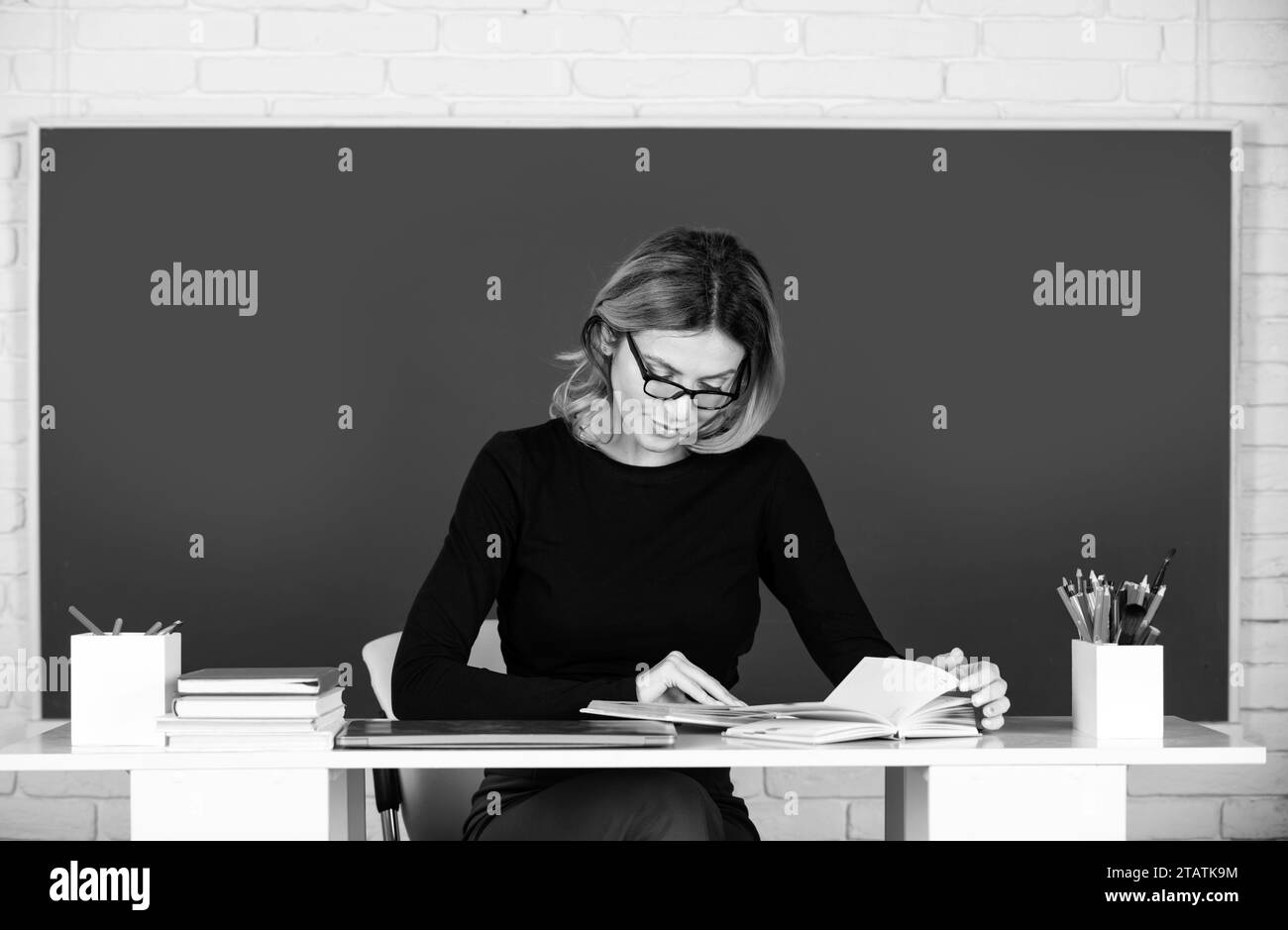 Portrait of female teacher teaching in classroom on blackboard. Education and tutoring concept ...