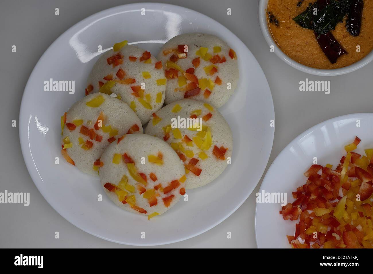 Savory bell pepper idly served with coconut chutney. A colorful and ...