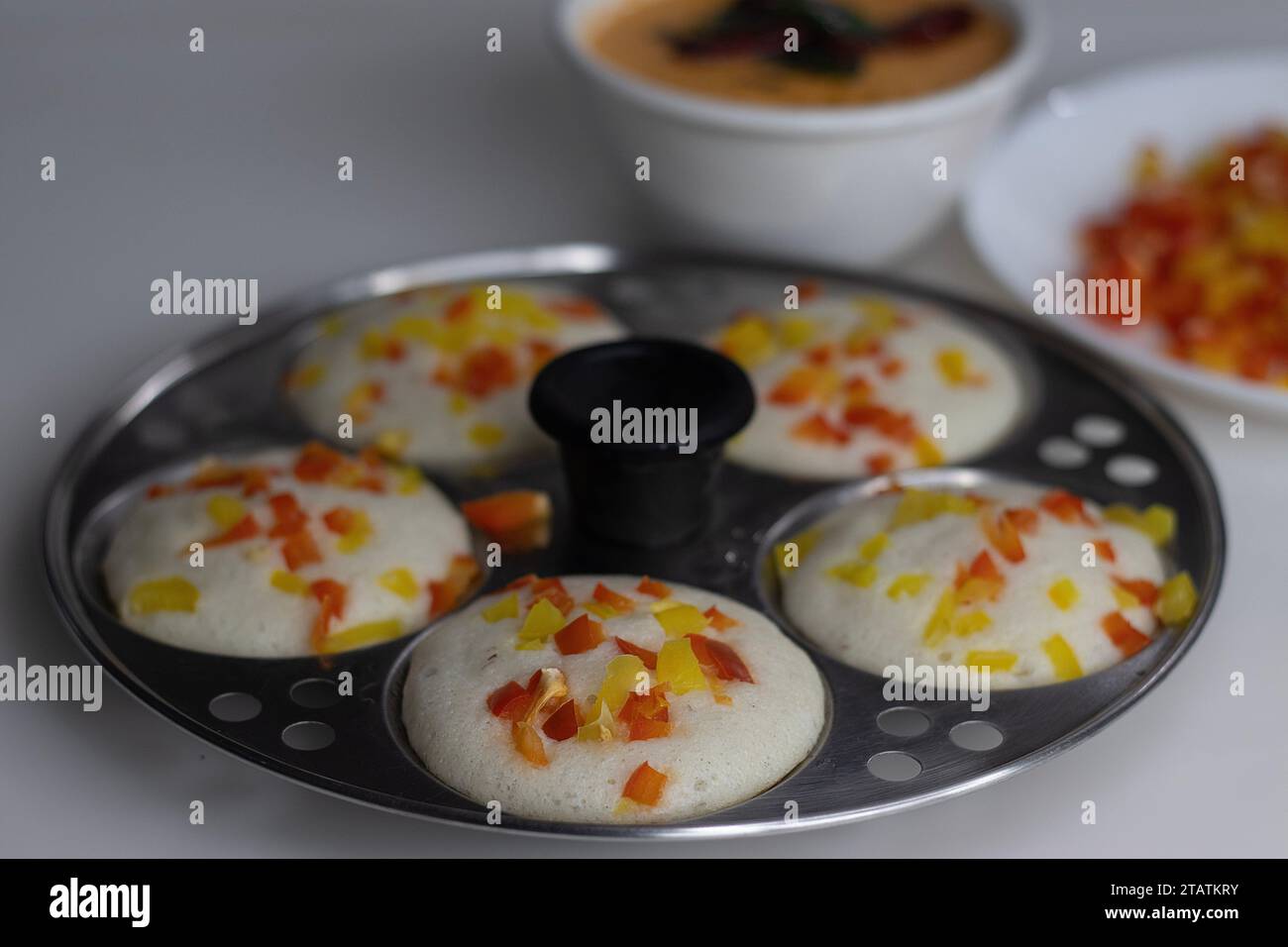 Savory bell pepper idly in idli mould, served with coconut chutney. A ...
