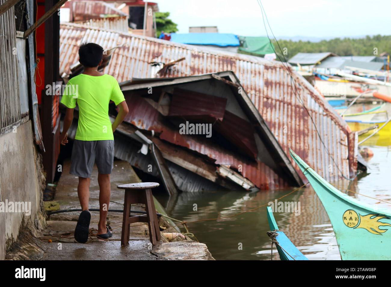 A resident walks past a toppled house caused by an earthquake at ...