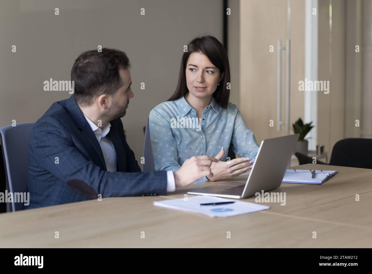 Colleagues engaged in teamwork in office using laptop Stock Photo - Alamy