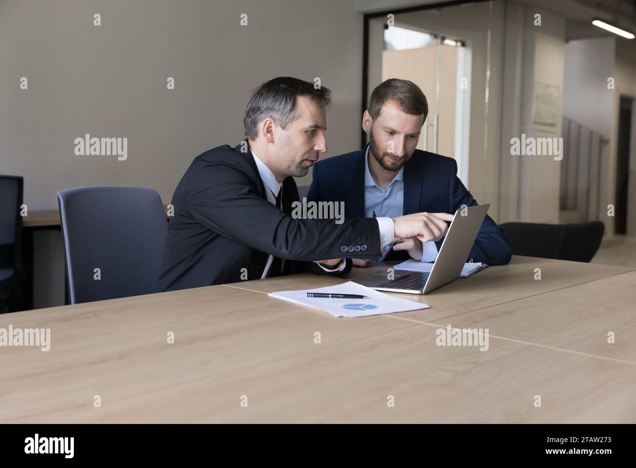 Two office employees using laptop, engaged in teamwork in office Stock ...