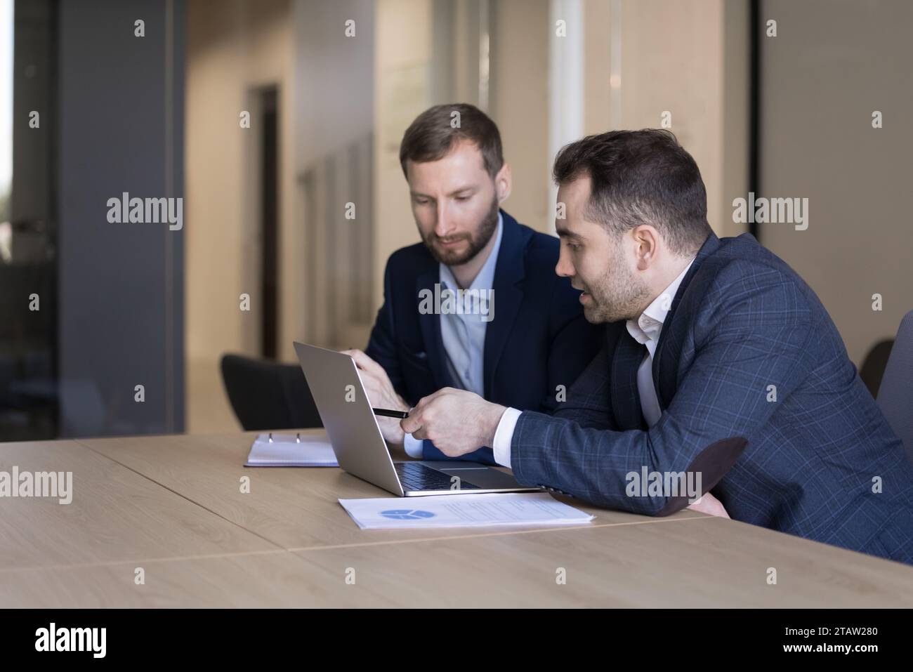 Two young male office employees review joint task use laptop Stock ...