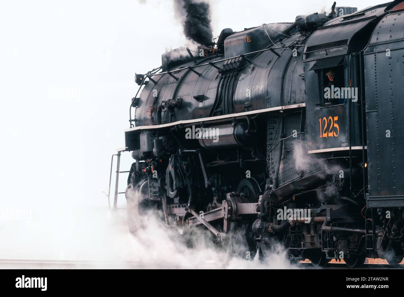 A black and white steam locomotive engine chugging along a winding ...