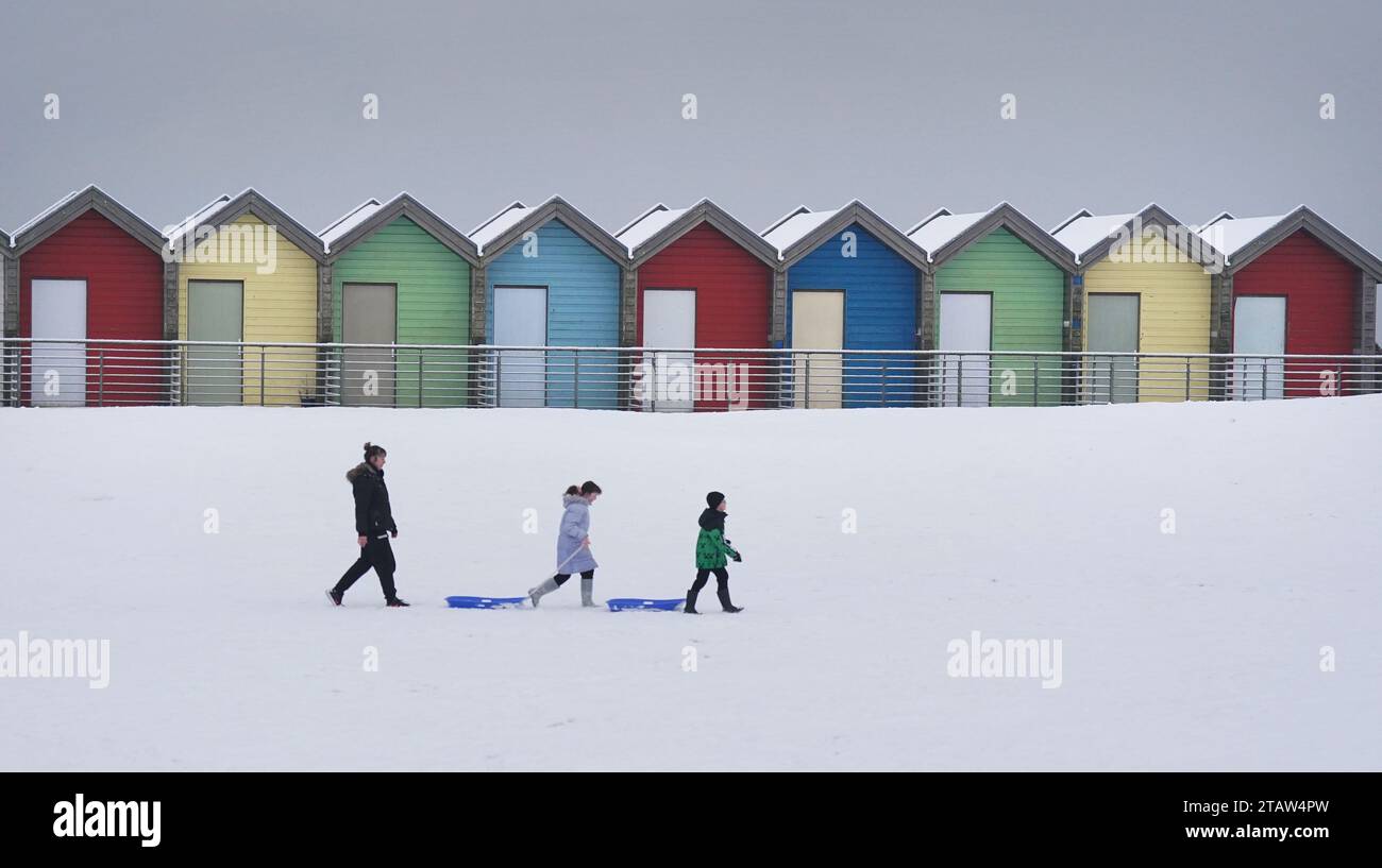People walk through the snow beside the beach huts at Blyth in ...
