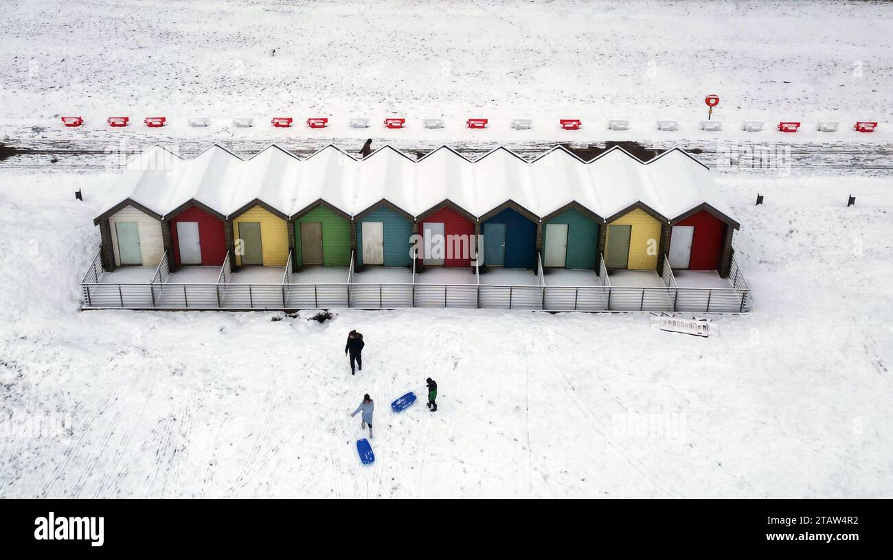 People walk through the snow beside the beach huts at Blyth in ...
