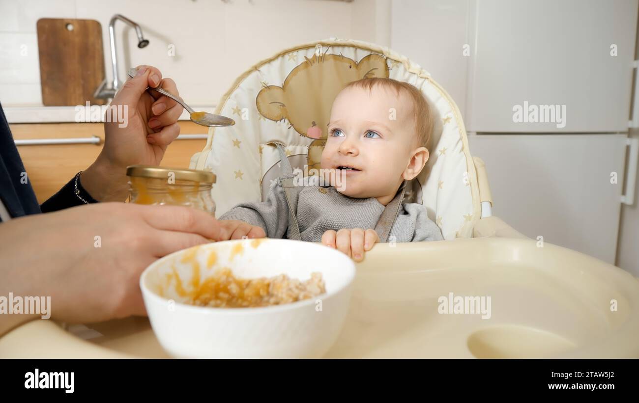 Portrait of little baby boy getting messy while eating porridge in ...