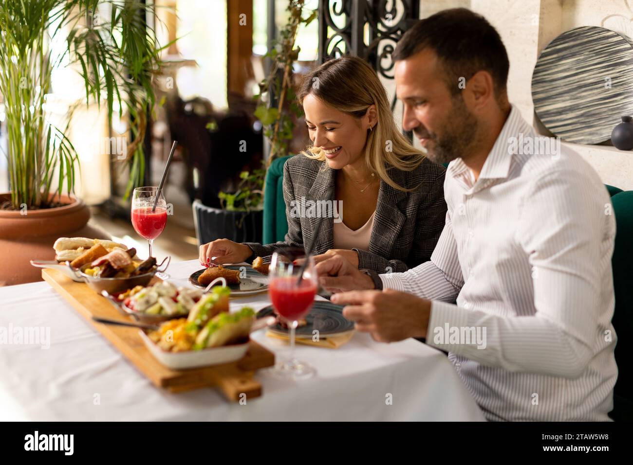 Young couple having a lunch and drinking fresh squeezed juice in the ...