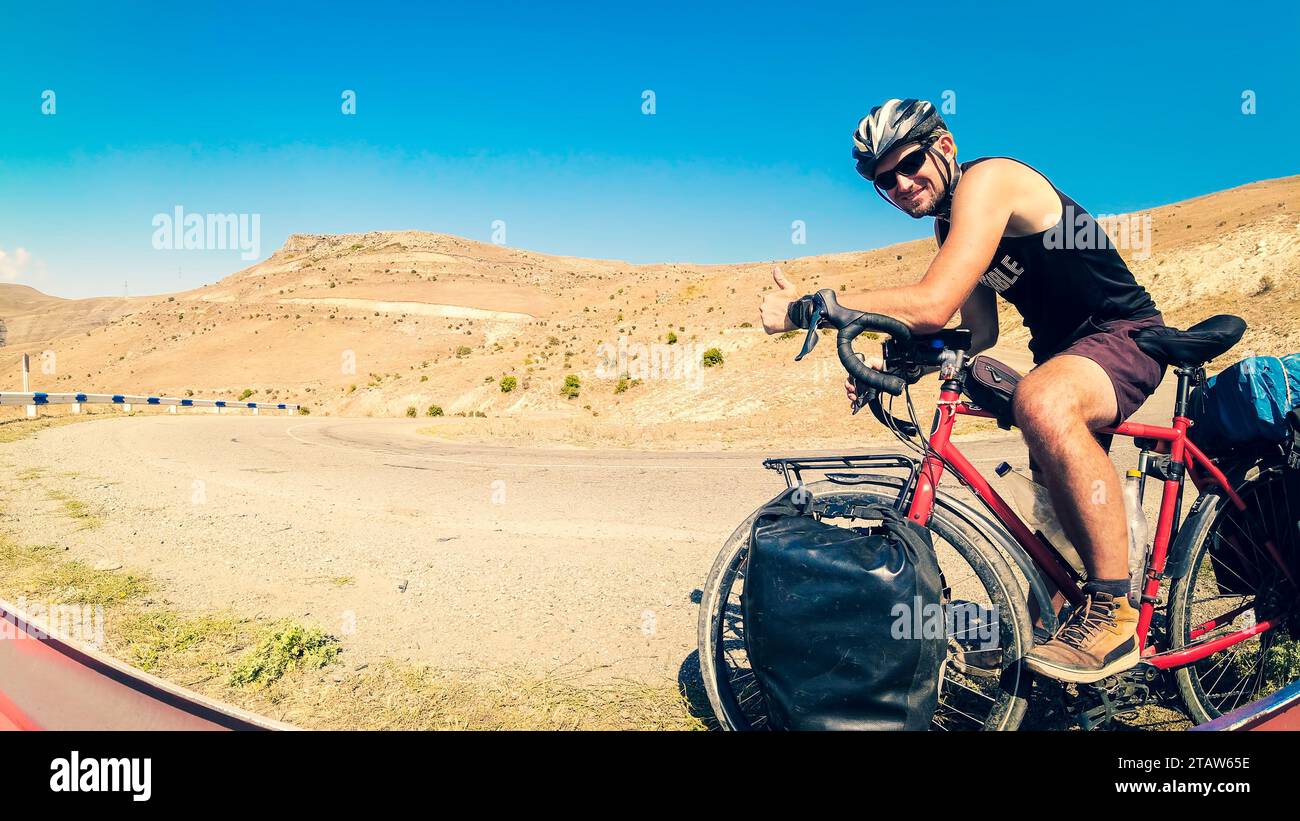 Caucasian male person stand by bicycle solo touring in tranquil countryside fully loaded with ...