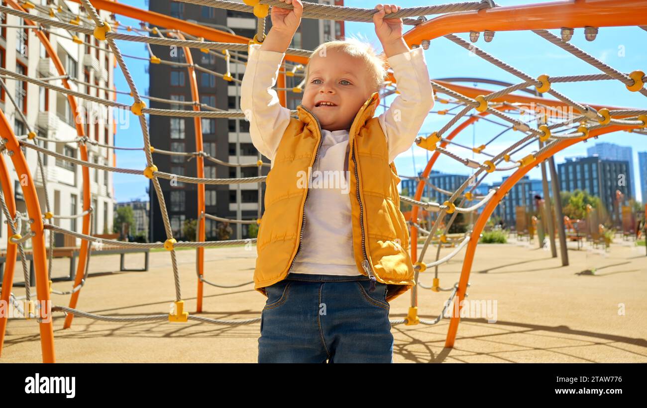 Cute baby boy climbing on the rope nets and running at playground ...