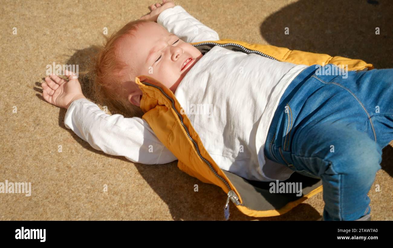 Very upset baby boy crying and falling on the ground on street. Upset ...