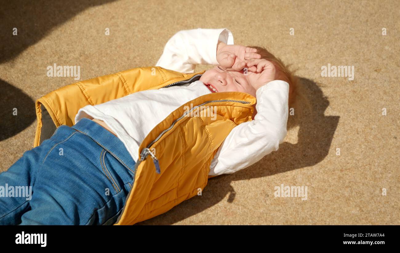 Upset crying and screaming toddler boy lying on ground at playground ...