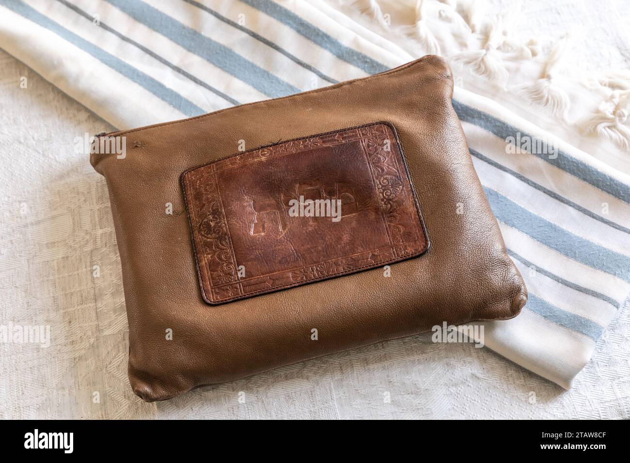 A brown Tallit bag written on it "Tallit" in Hebrew, and a blue and ...