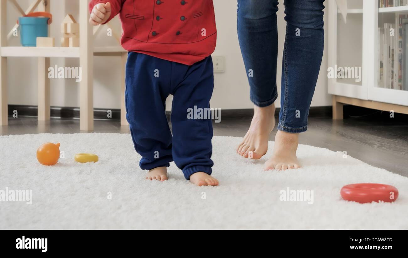 Closeup of little baby's feet learning walking with mother on soft ...