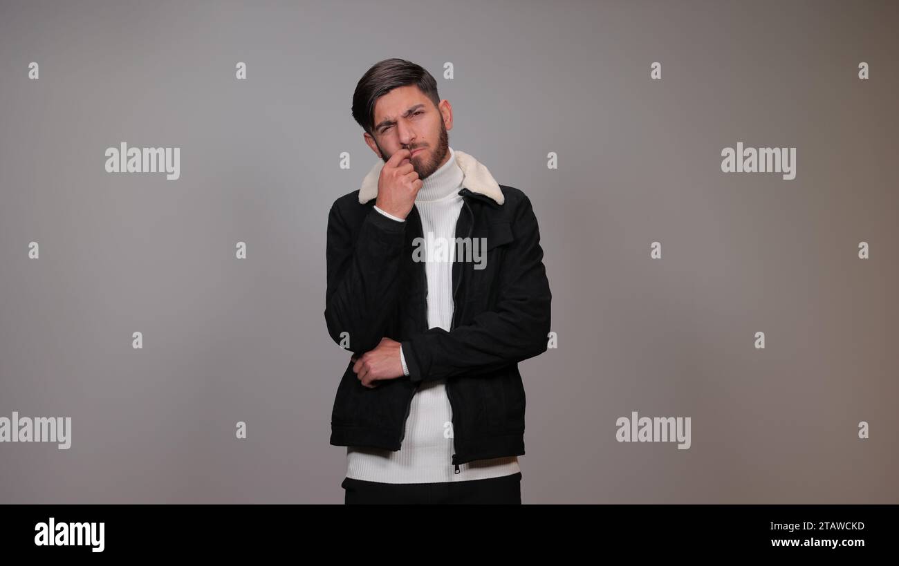 A confused young man thinking against a gray background Stock Photo - Alamy