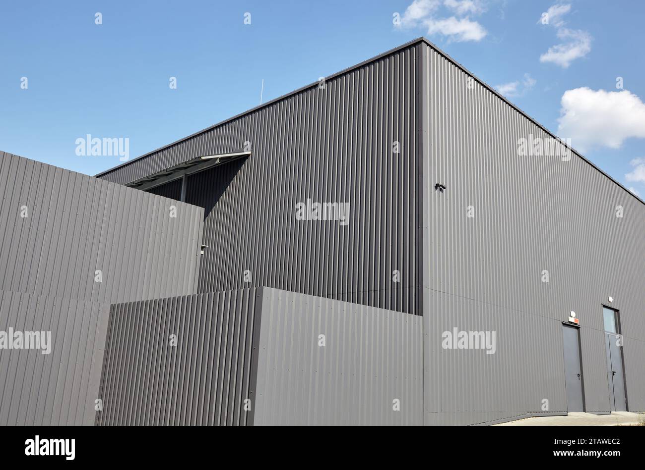 Corrugated steel warehouse or factory industrial building against blue ...
