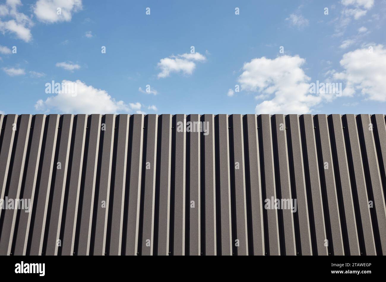 Corrugated steel fence against blue sky. Corrugated metal texture ...