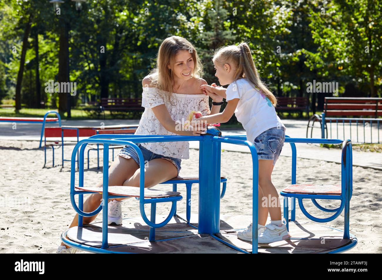 Mother and daughter play on the playground in the summer city park ...