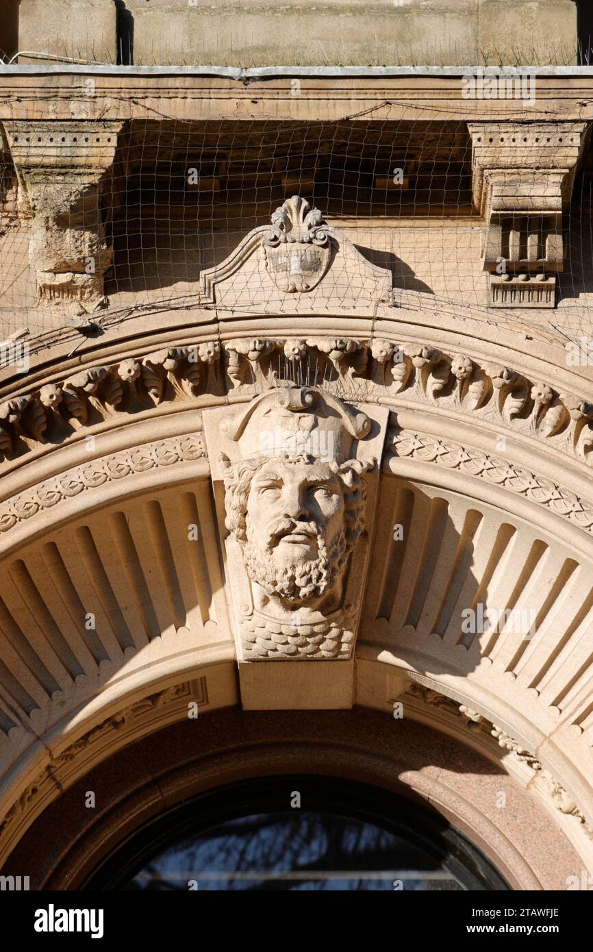 Ribbed stone arch with grotesque head of plutus keystone in old bank ...