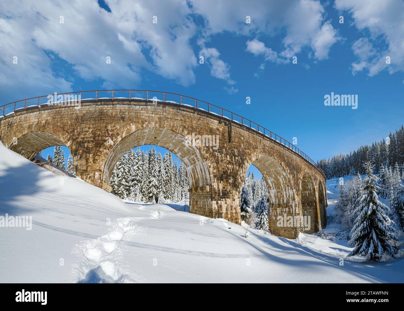 Stone viaduct (arch bridge) on railway through mountain snowy fir ...