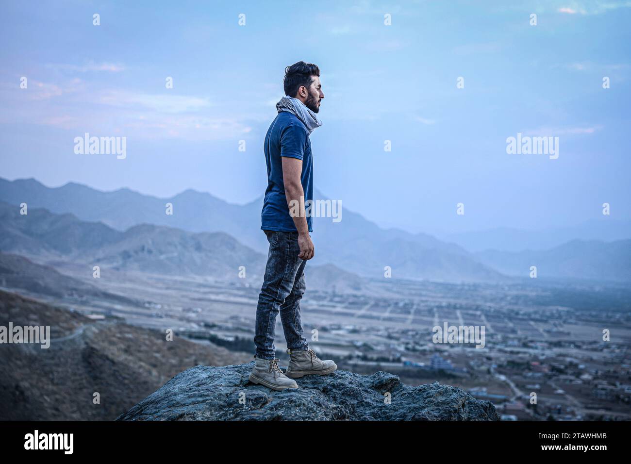 A young man hiking on top of snowy mountains during the winter season ...