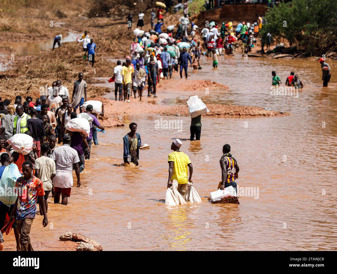 (231203) -- MADOGO, Dec. 3, 2023 (Xinhua) -- People wade through the ...