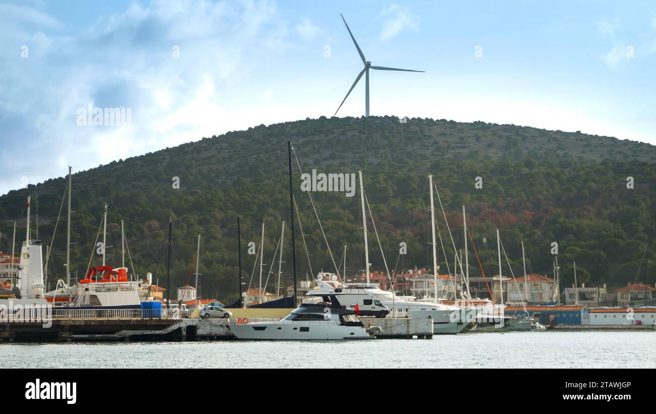 Wind turbine located on the hill top next to the sea port with moored ...