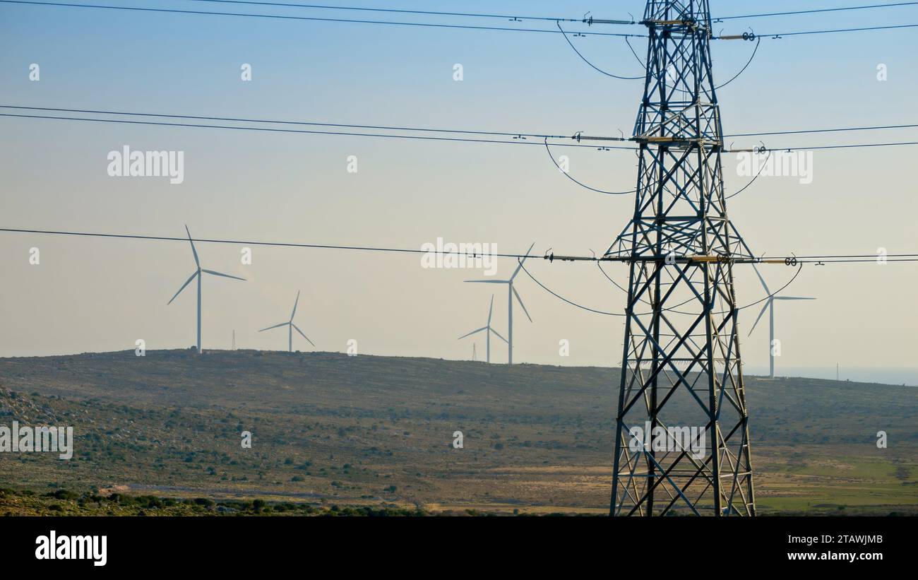 Valley with rotating wind turbines and high voltage power lines ...