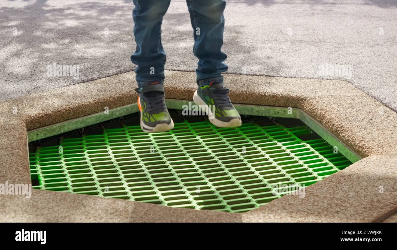 Closeup of child's feet jumping on the outdoor trampoline at kids ...